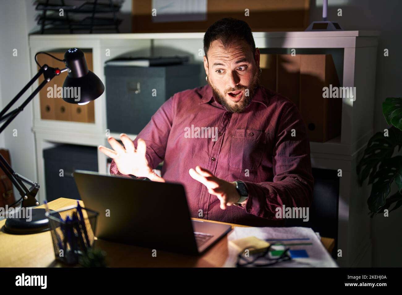 Plus size hispanic man with beard working at the office at night afraid ...