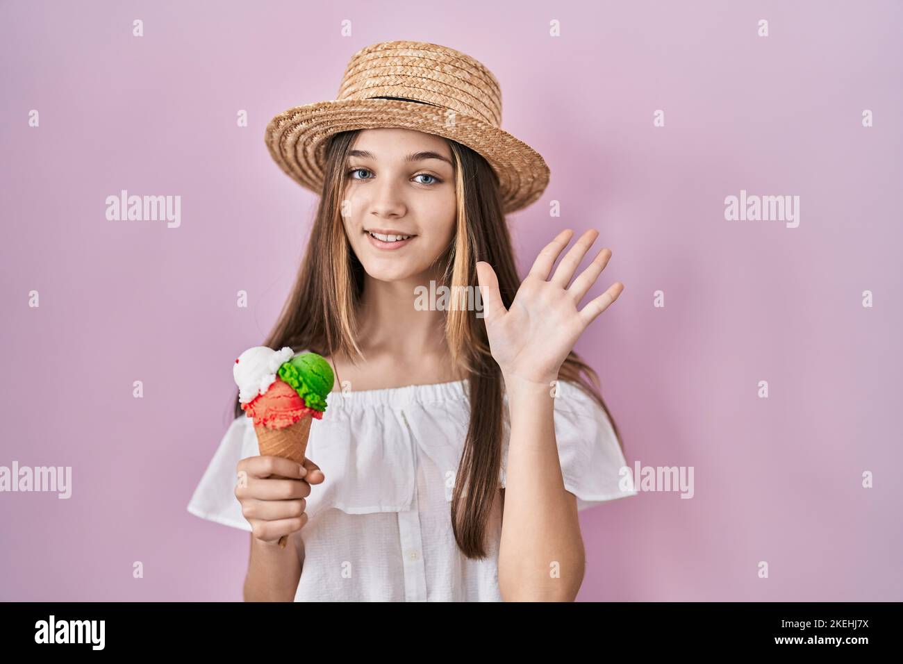 Teenager girl holding ice cream waiving saying hello happy and smiling ...