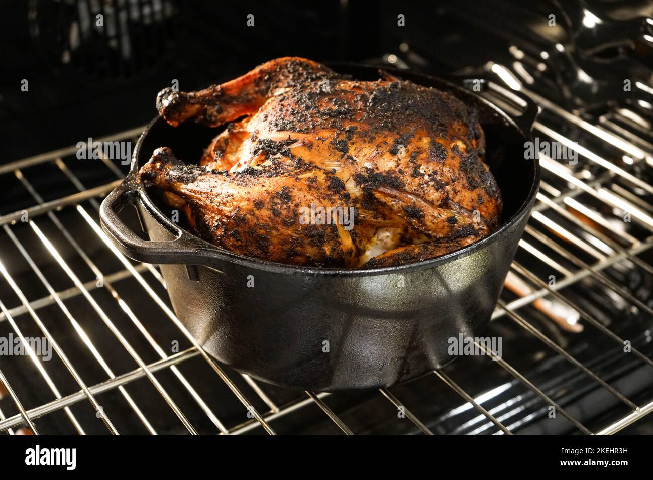 Seasoned whole chicken roasting in a cast iron pot in oven Stock Photo ...