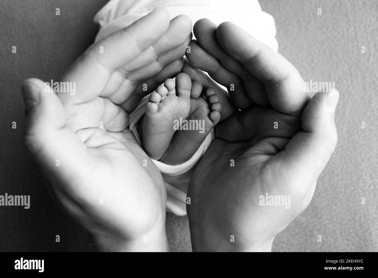 The palms of the parents. Father and mother hold the legs of a newborn ...