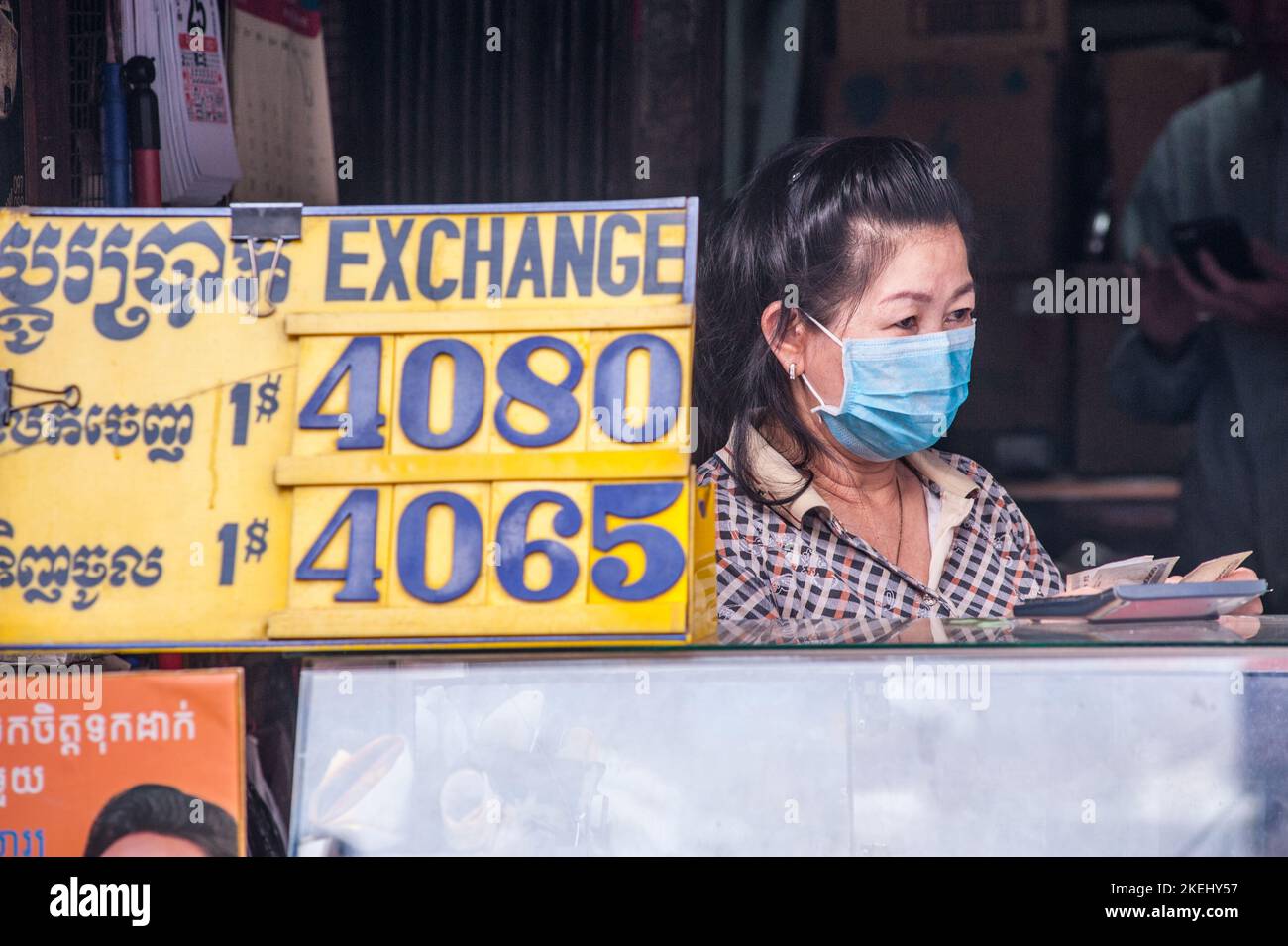A Cambodian woman at a money exchange booth counts Khmer riel notes ...
