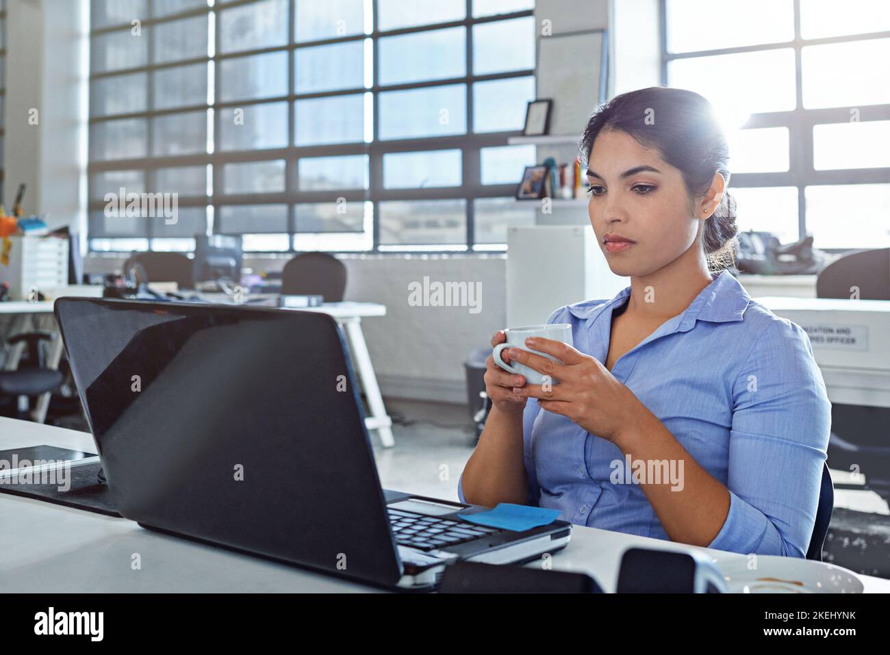 Catching up on emails during her coffee break. a young businesswoman ...
