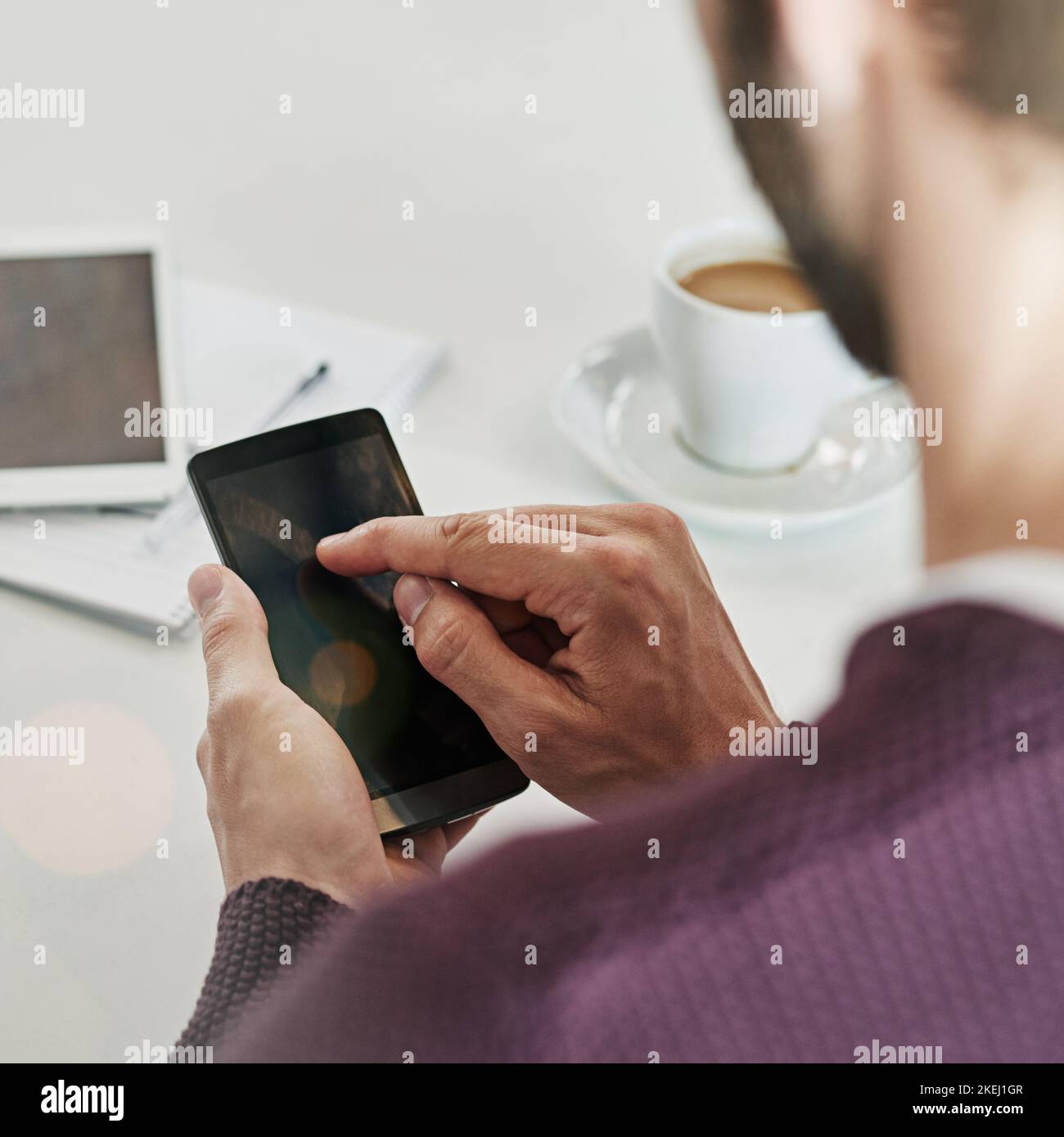 Adding important contacts to his phone. a young man using a phone at ...