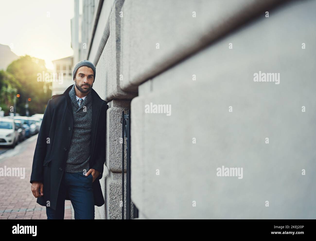 Walking the streets in style. a fashionable young man leaning against a ...