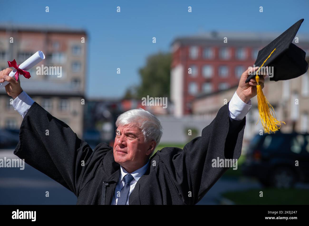 An elderly gray-haired man in a graduate robe spread his arms to the ...