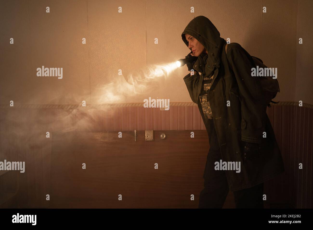Woman explorer with flashlight inside corridor or tunnel of ruined ...