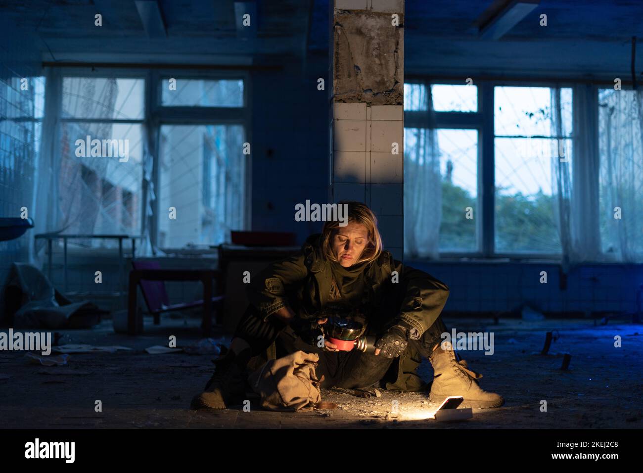 Post-apocalypse. a young woman sits in an abandoned building on the ...