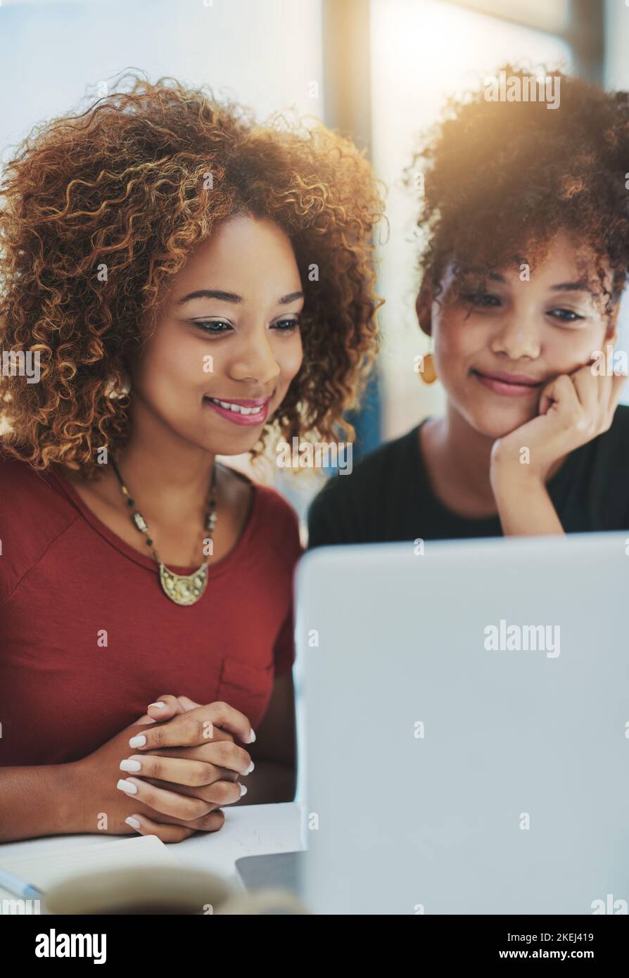 Putting their heads together. two young designers working on a laptop together Stock Photo - Alamy