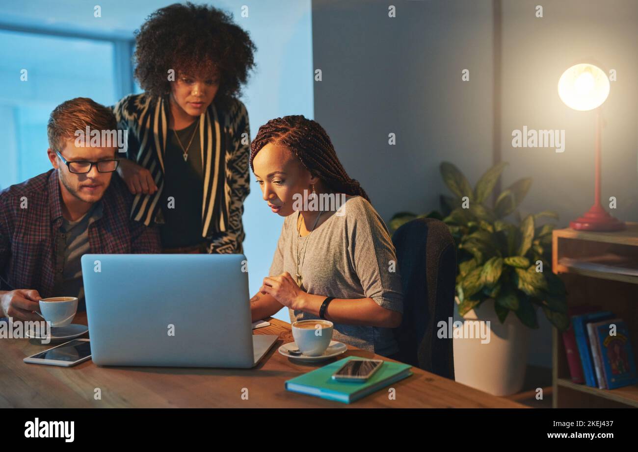 Meeting deadlines with teamwork. a group of young people working late ...