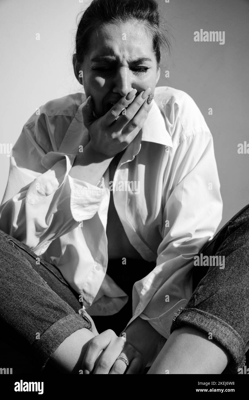 serious young woman feeling sad and scared, depressed. Sitting on white ...