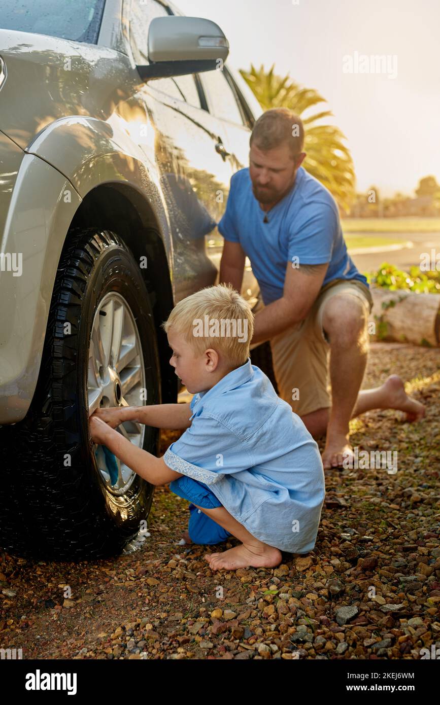 Giving the car a good scrub. a father and son washing a car together ...