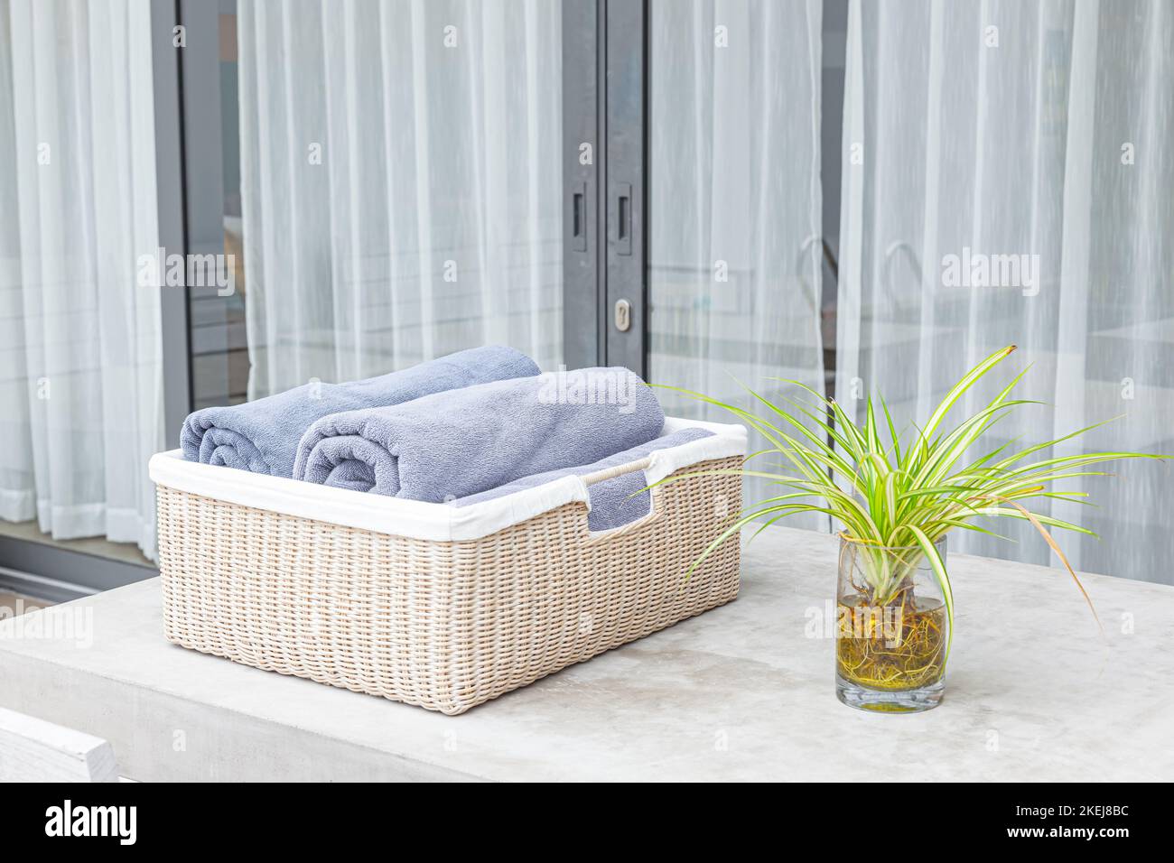 Blue bath towels in wicker basket on concrete table in sunny garden ...