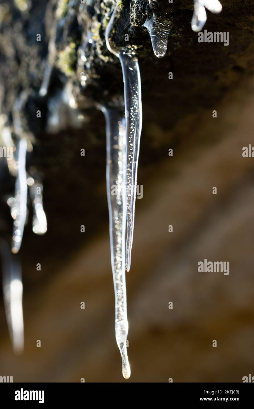 A vertical closeup of a sharp icicle hanging from a wall Stock Photo ...