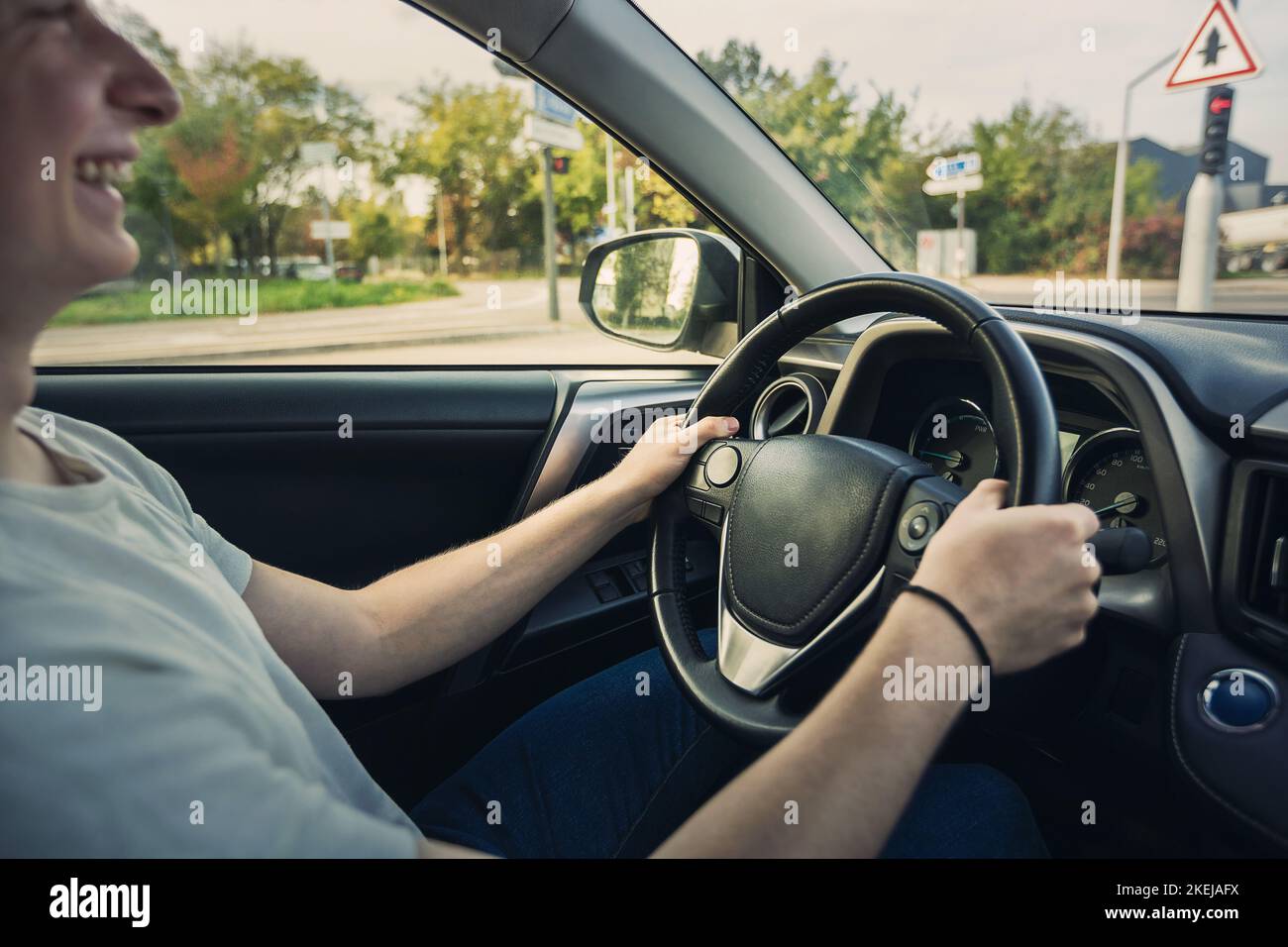 Joyful boy teenager driving car confident. Happy young man driver ...