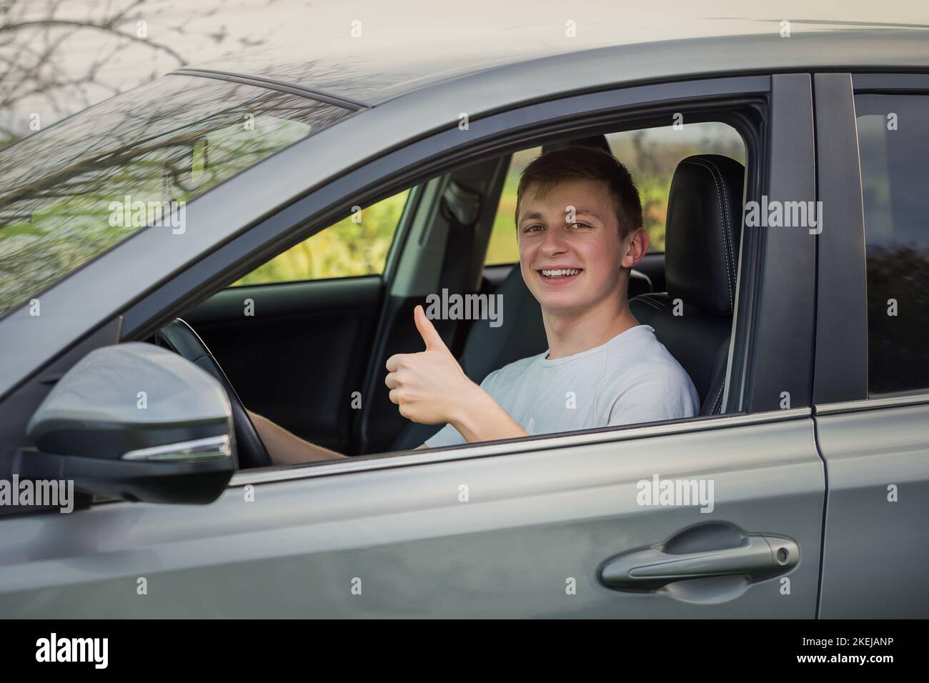 Positive young man driver showing thumb up gesture sitting in front of ...