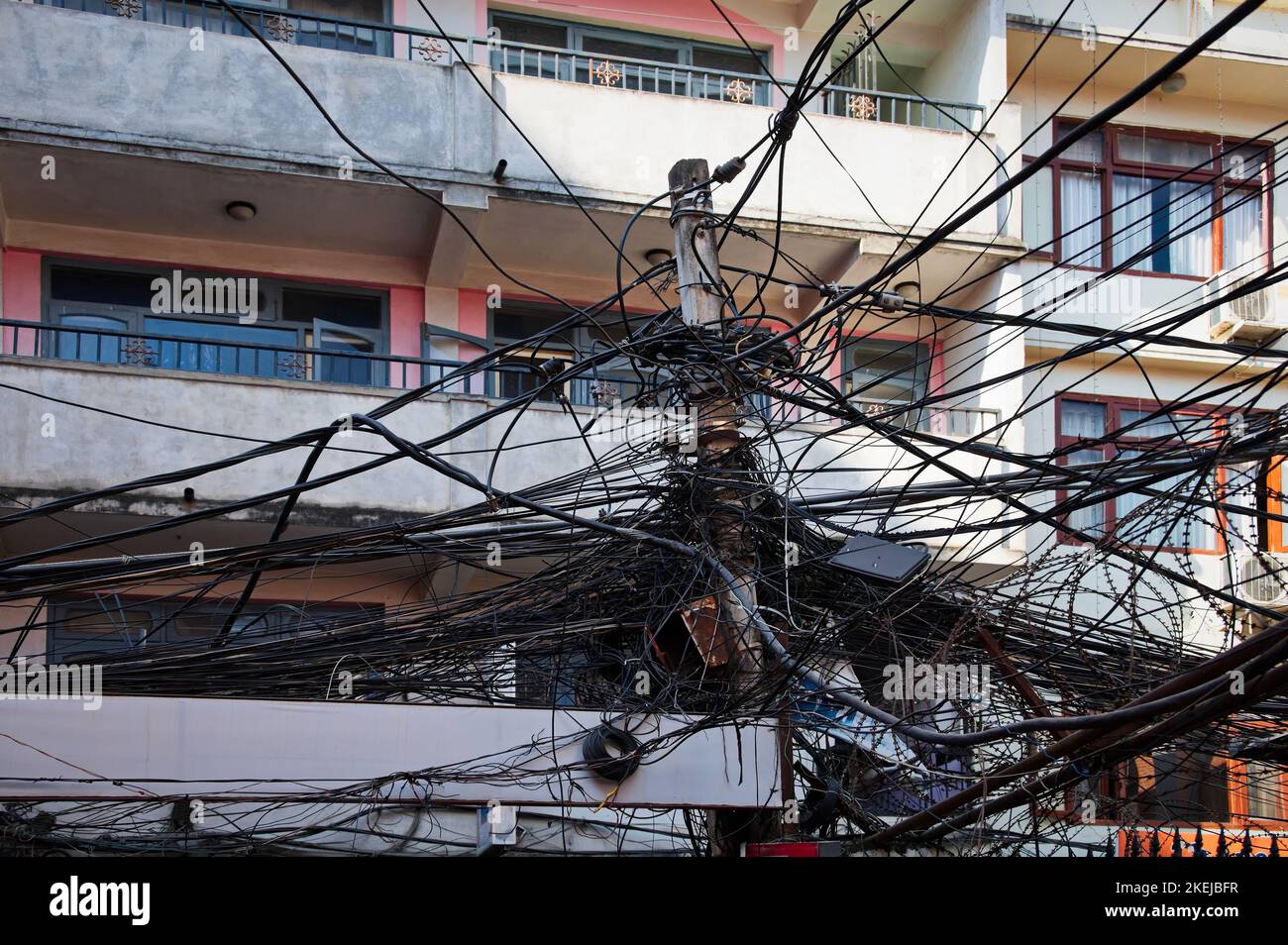 Bunch of electrical wires attached to a pole with building in ...
