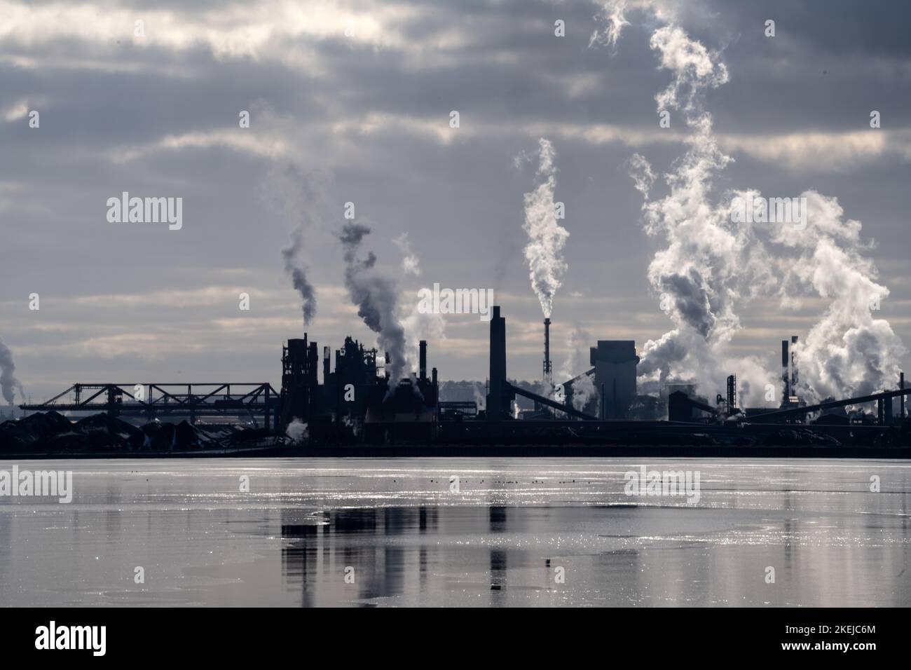 A smoking factory reflecting on a lake on a cloudy day in Hamilton ...