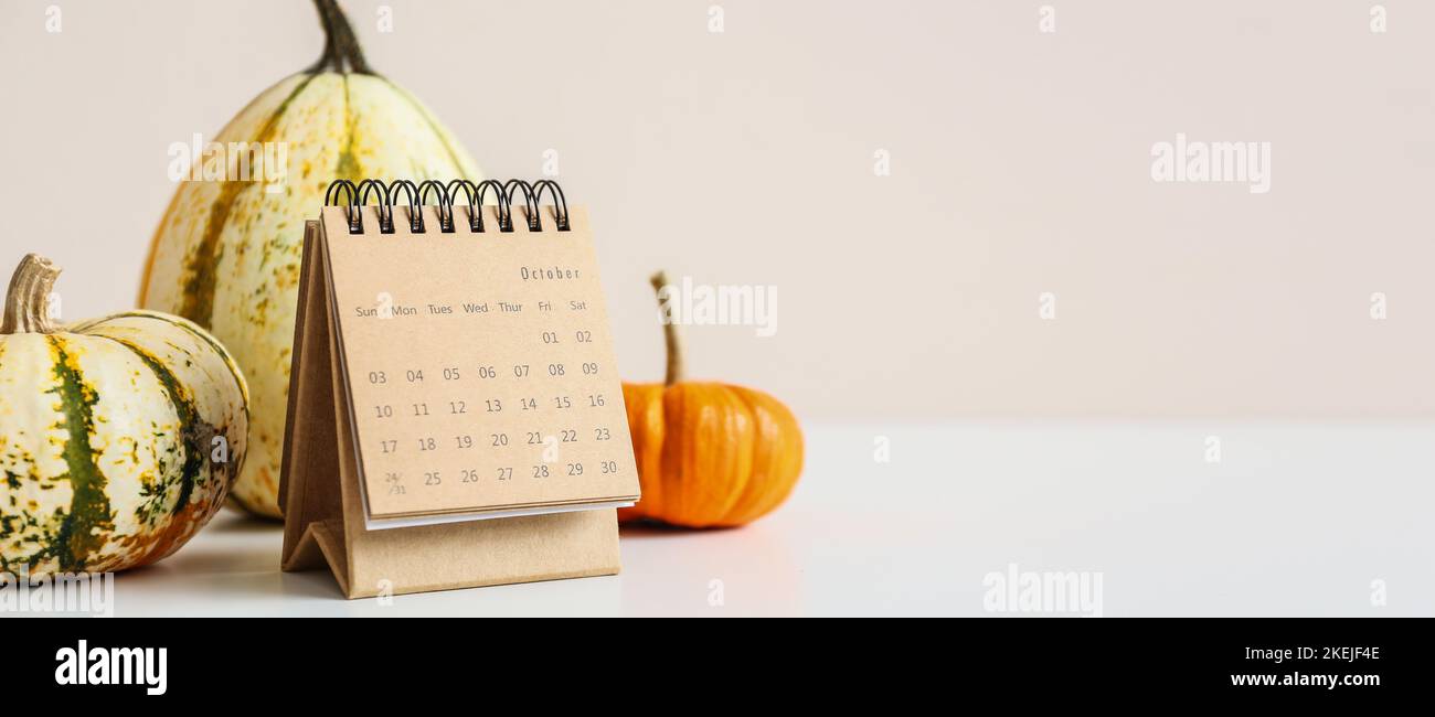 Calendar with open page of October month and pumpkins on light ...