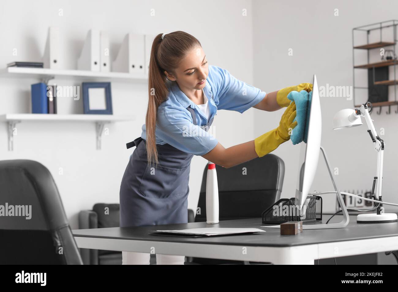 Female worker of cleaning service wiping computer screen in office ...