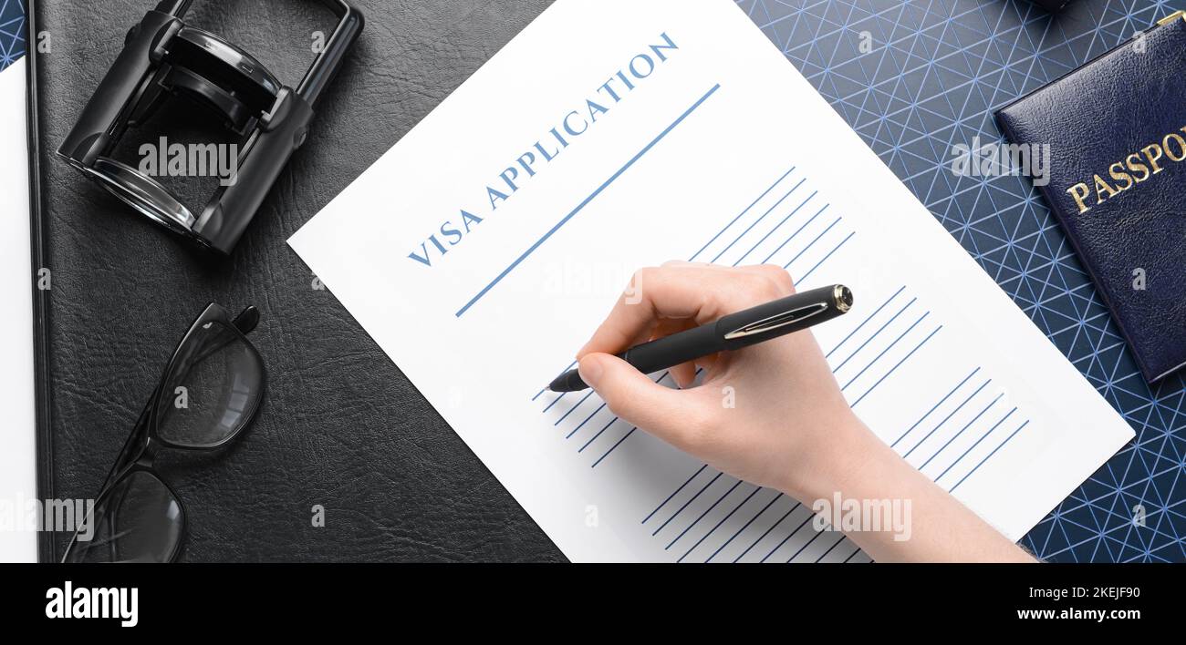 Woman filling in visa application form at table, top view. Concept of ...