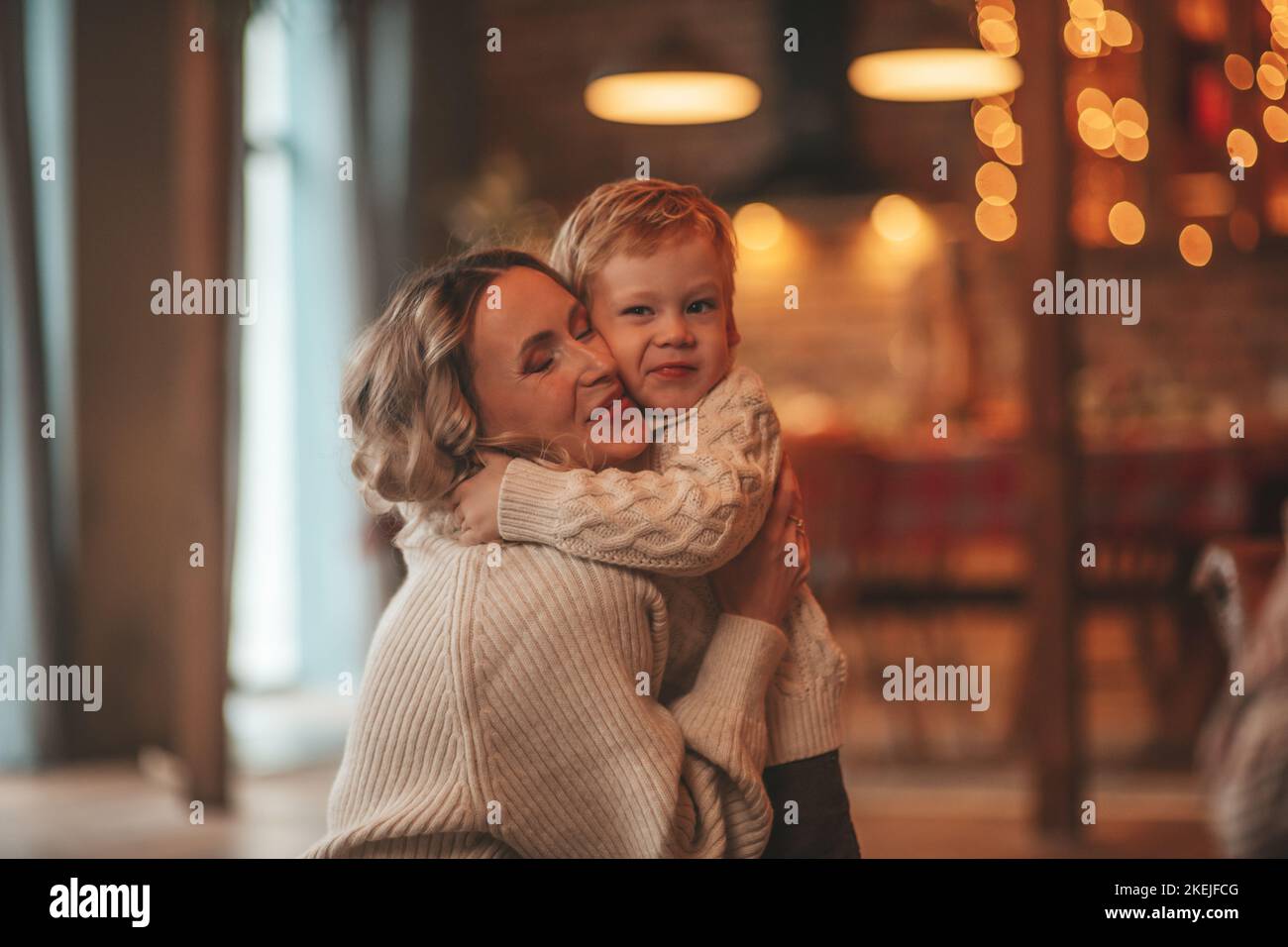 Portrait of happy family mom with small son in knitted beige sweaters ...