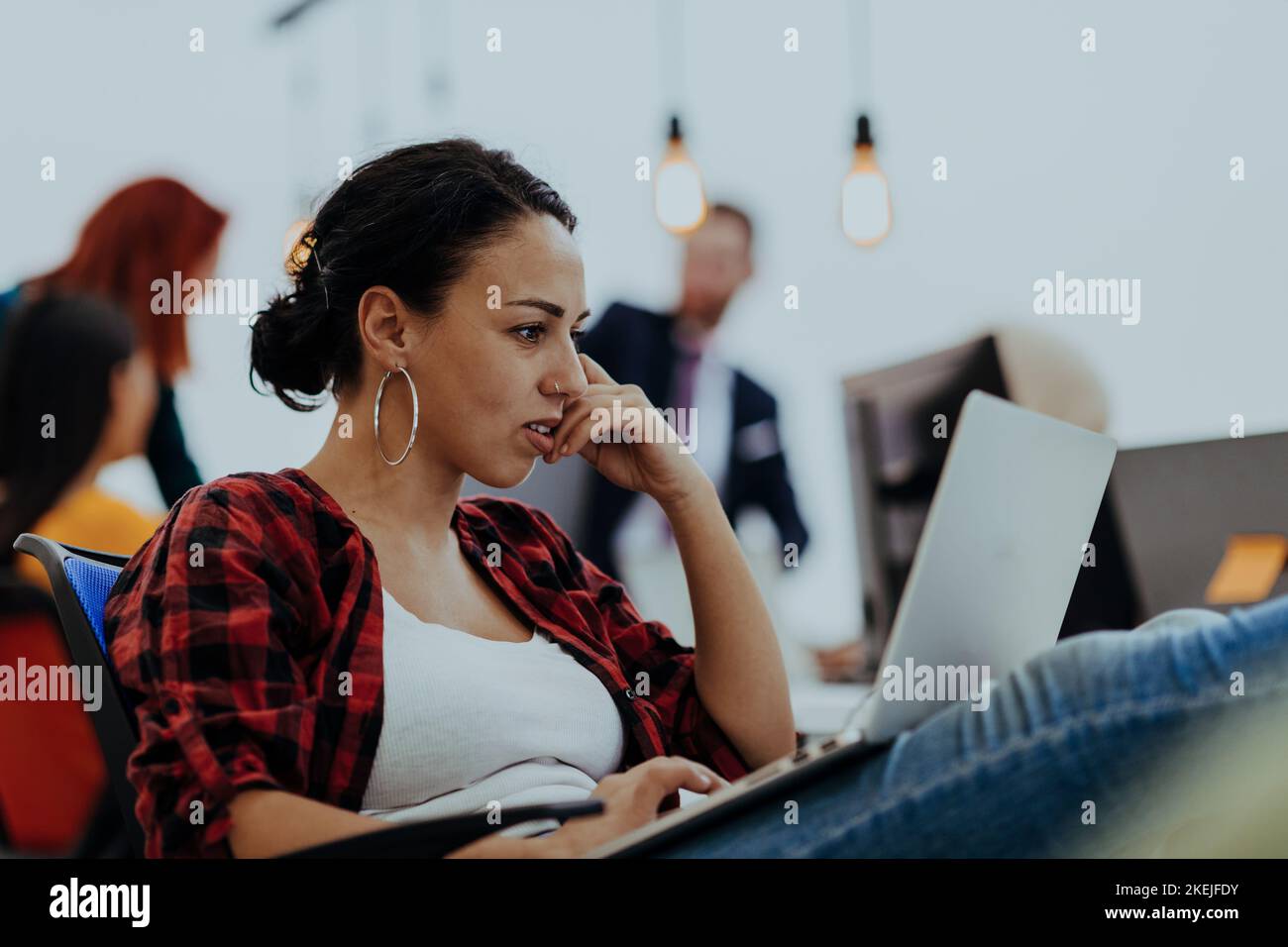 Happy woman working on laptop in modern office surrounded by friends ...