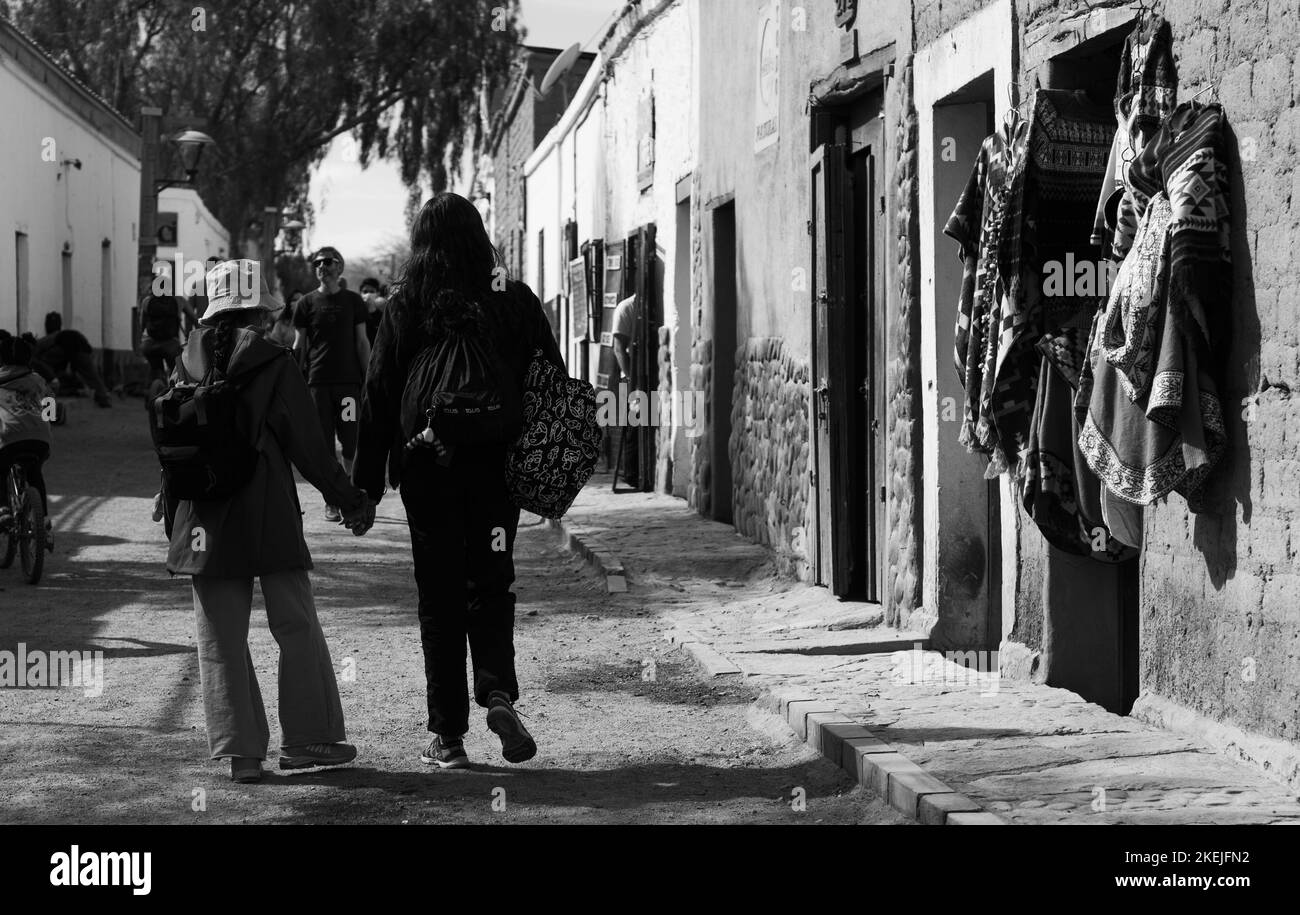 A Grayscale Of A Couple Holding Hands And Walking In The Streets Of