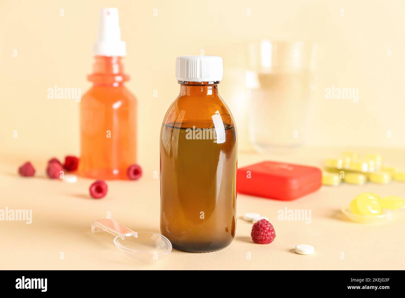 Cough syrup with spoon, raspberries and pills for sore throat on beige ...