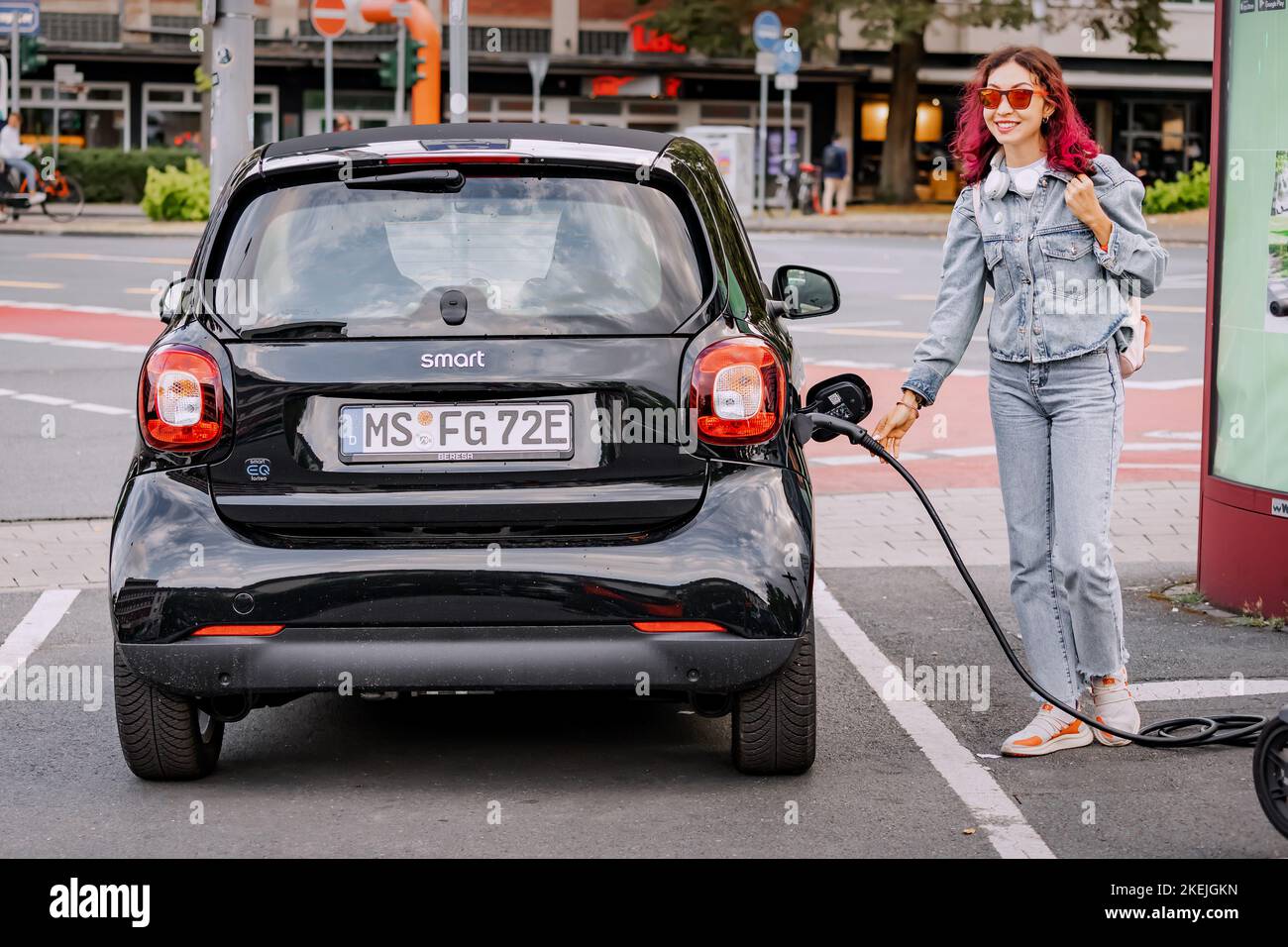 26 July 2022, Munster, Germany: A girl charges her Smart car for two in ...