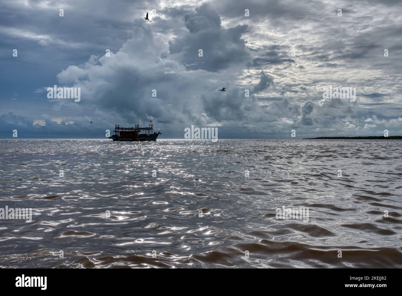 distance view of fishing boat sailing at the horizon Stock Photo - Alamy