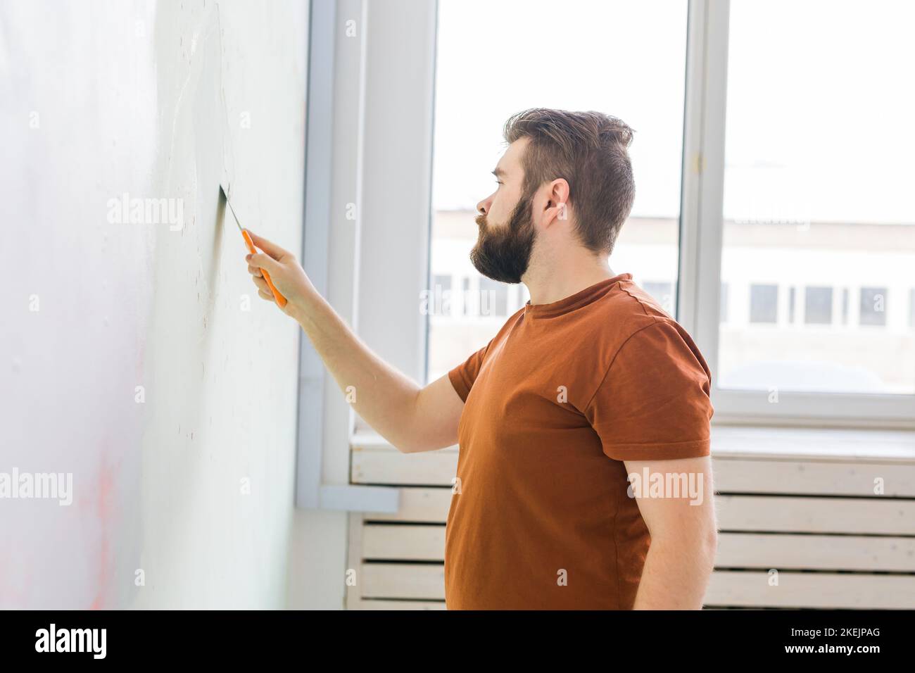 Young man using spatula and plastering of wall with white fresh ...