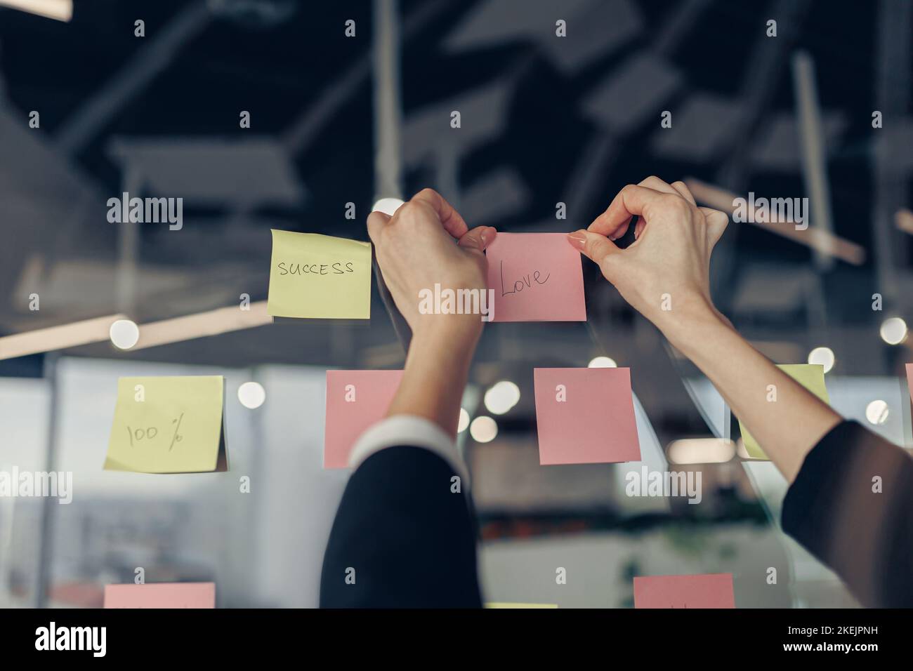 Businesswoman hand's is sticking sticky notes on motivation board in ...