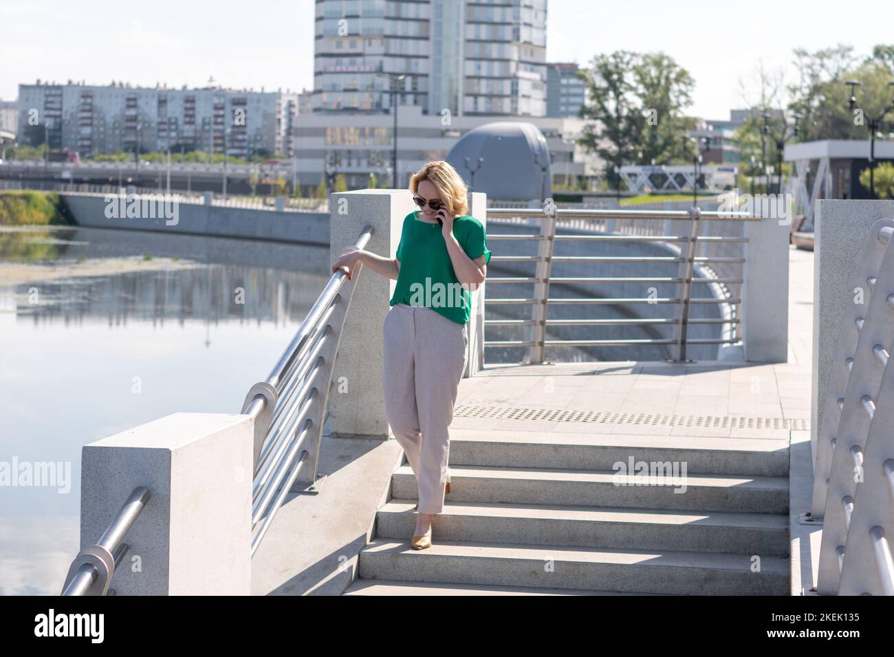 A smiling student girl wearing sunglasses, talking on a mobile phone ...
