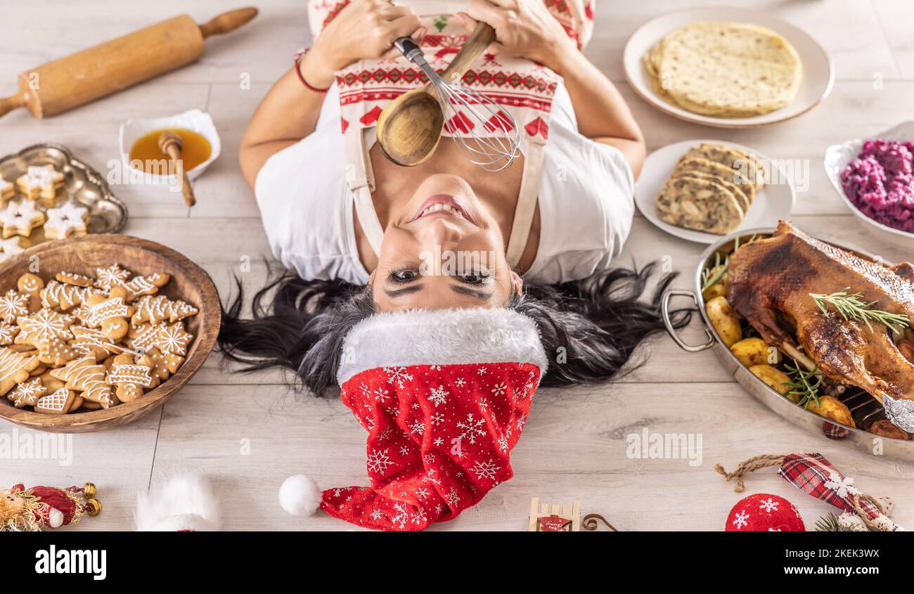 Back view of a female cook in a Christmas apron and Santa hat lying on ...