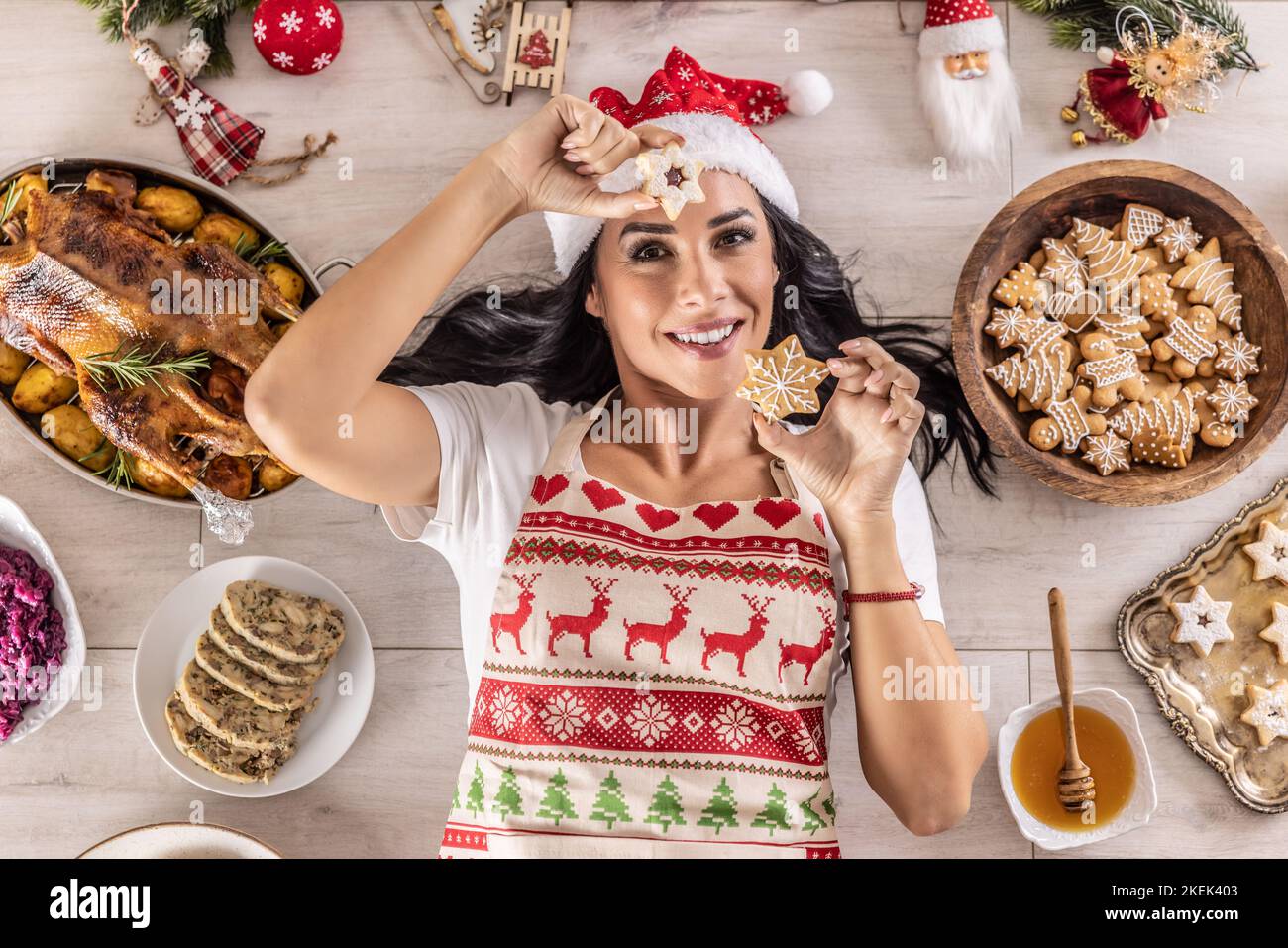 A cheerful cook in a Christmas apron is lying on the ground holding a ...
