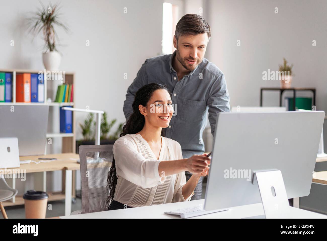 Smiling millennial european female showing to man manager with hand in ...