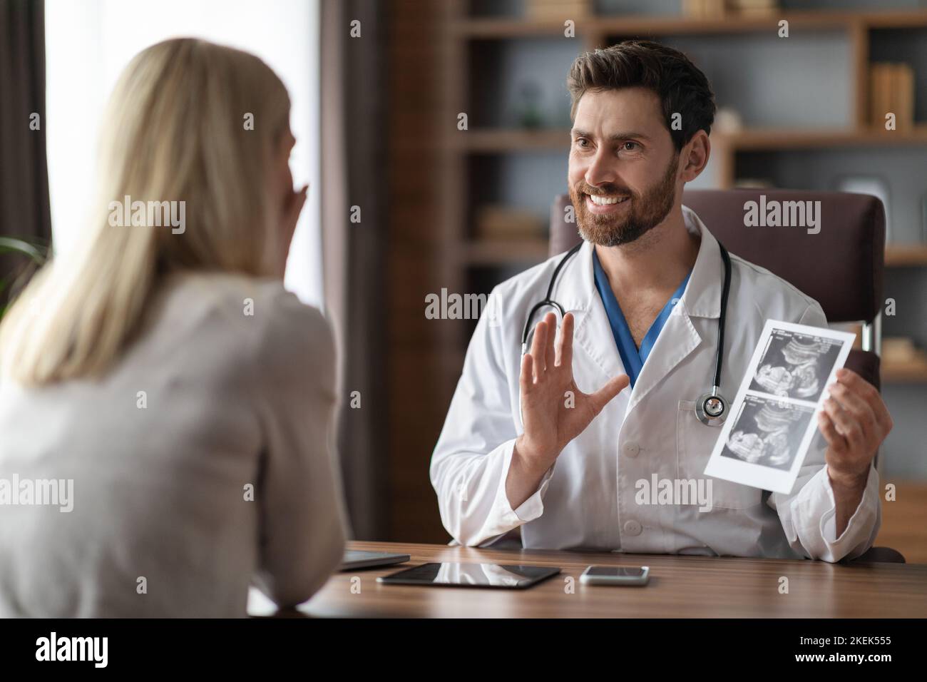 Smiling Gynecologist Doctor Showing Baby Sonography Image To Pregnant ...