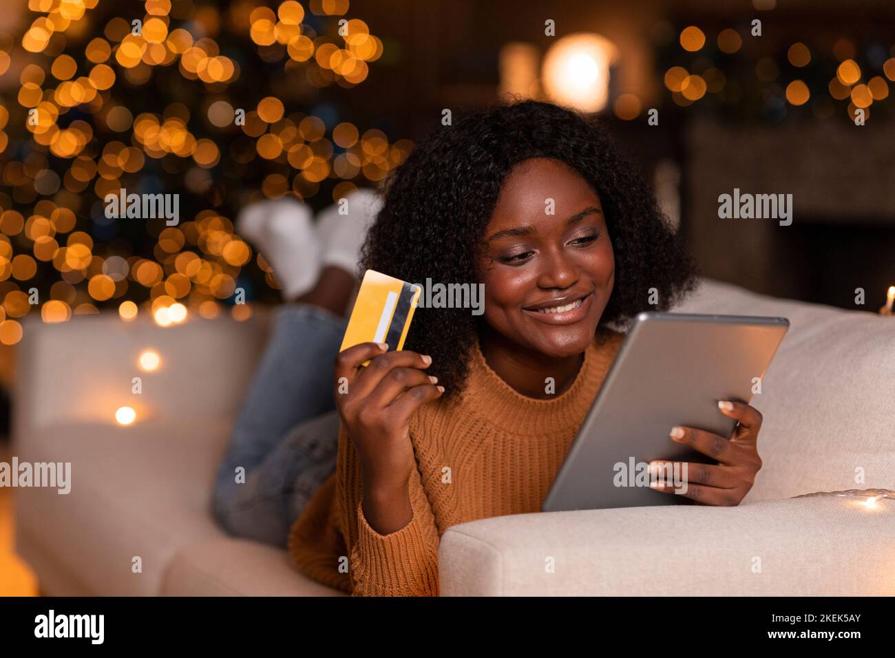 Smiling young african american woman watch video on tablet use credit ...