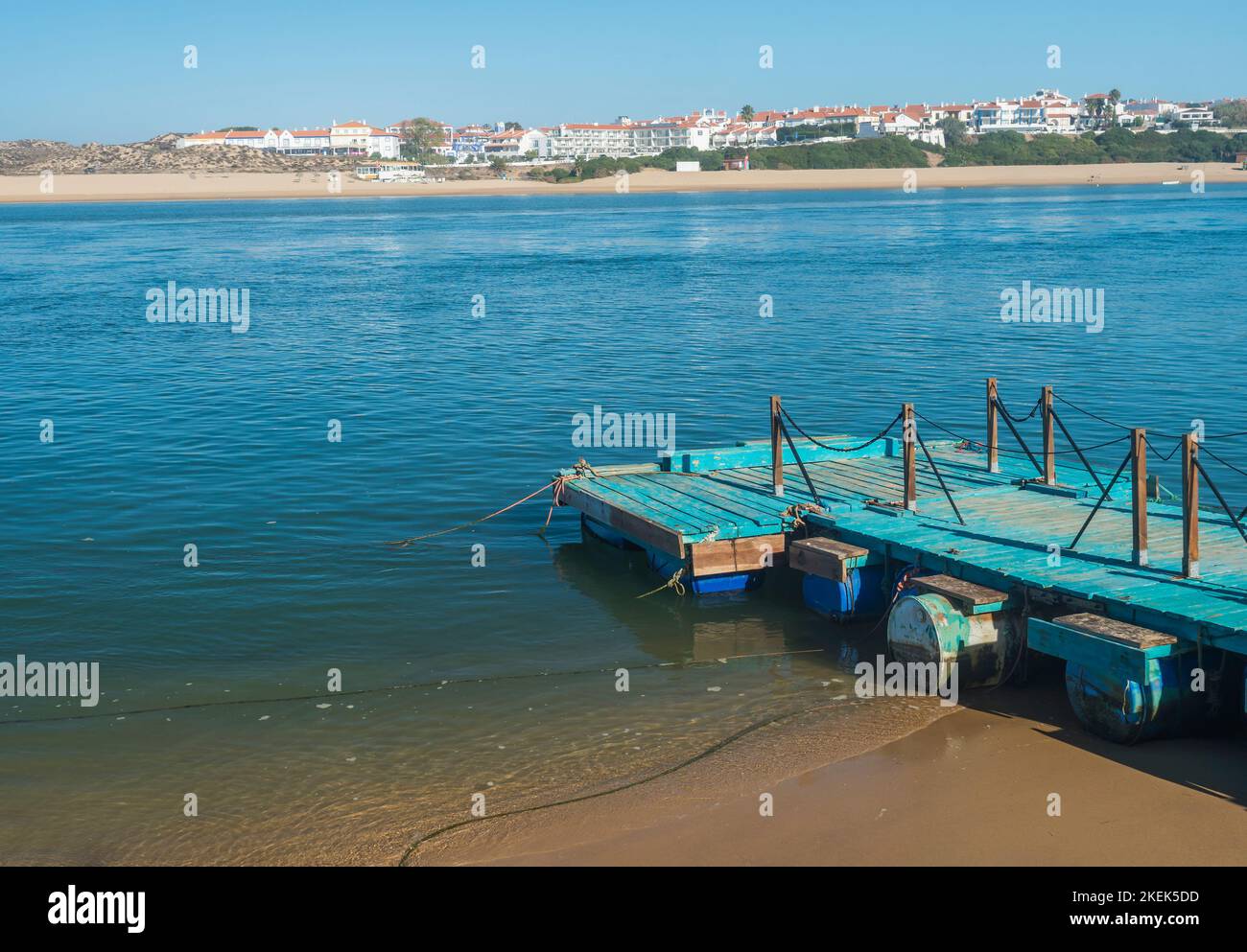 Small turquoise wooden pier at Praia das Furnas sand beach with view ...