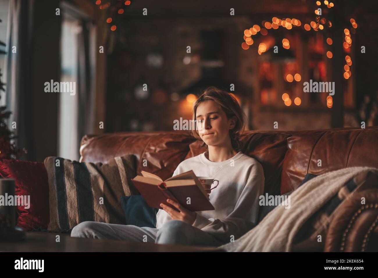 Young teen boy with long hair holding and reading study book for ...