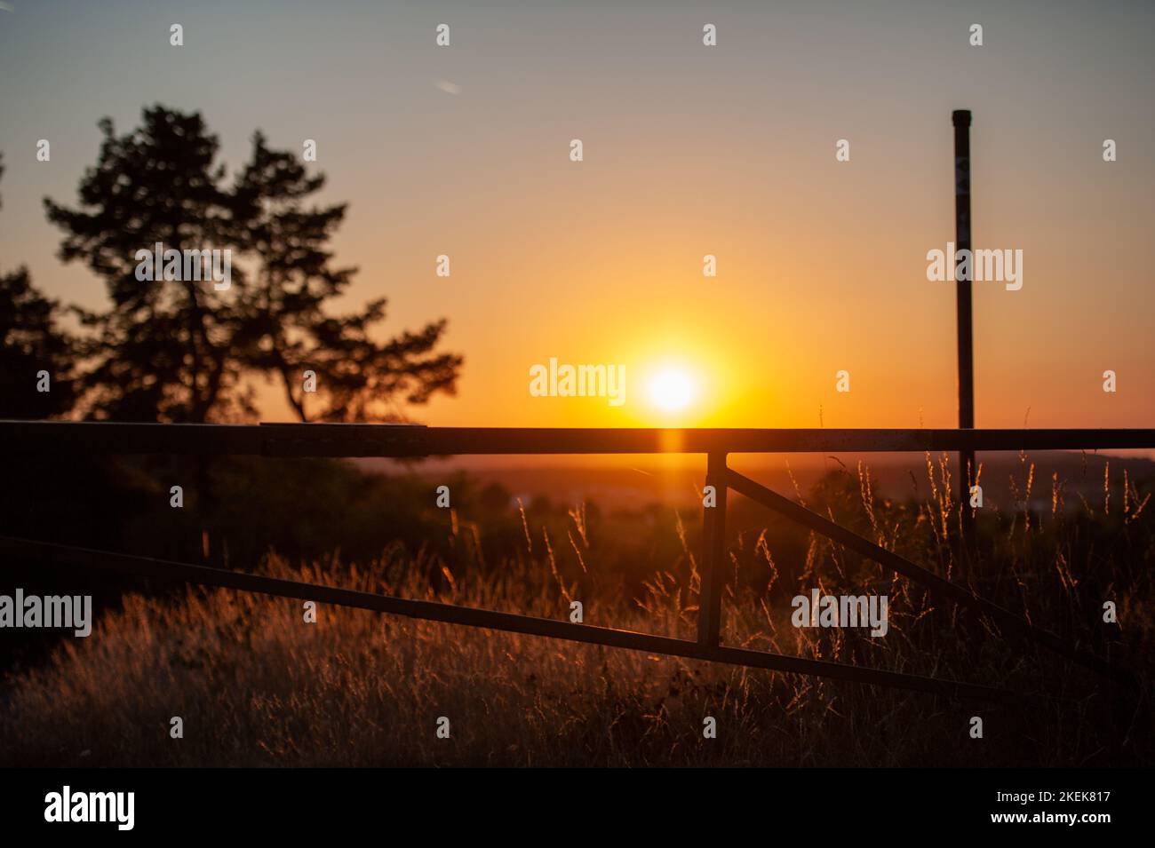 A beautiful sunset with the sun shining above a gate in Germany Stock ...