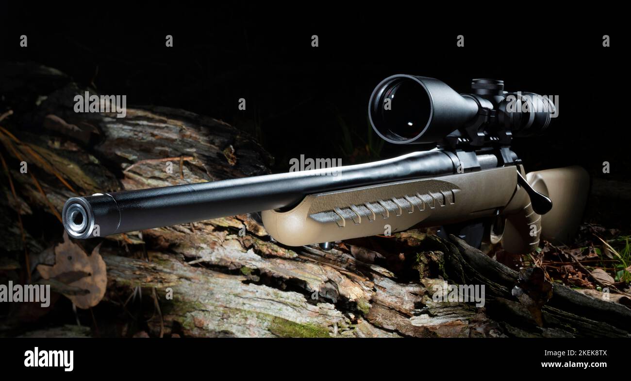 High powered riflescope on a bolt action hunting rifle in a dark forest ...