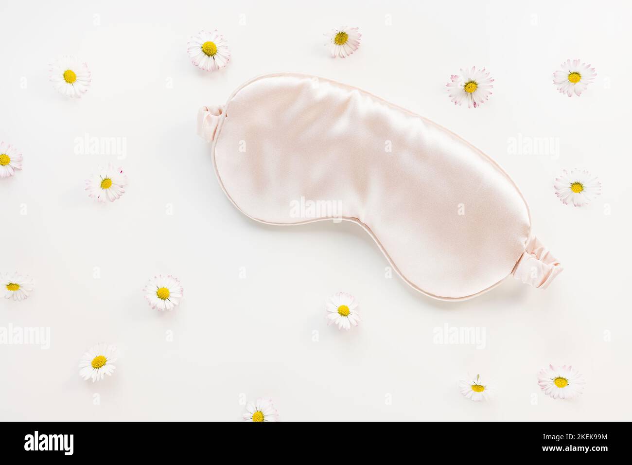 Pink satin eye sleeping mask and fresh spring or summer daisy flowers ...