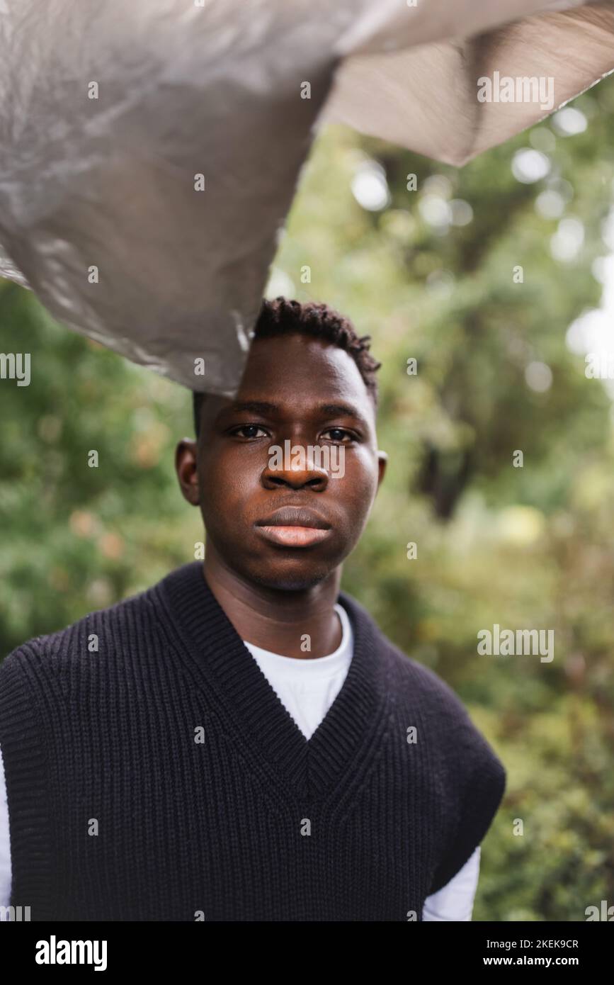 Young African man outdoor throwing plastic trash bag in the air, street ...