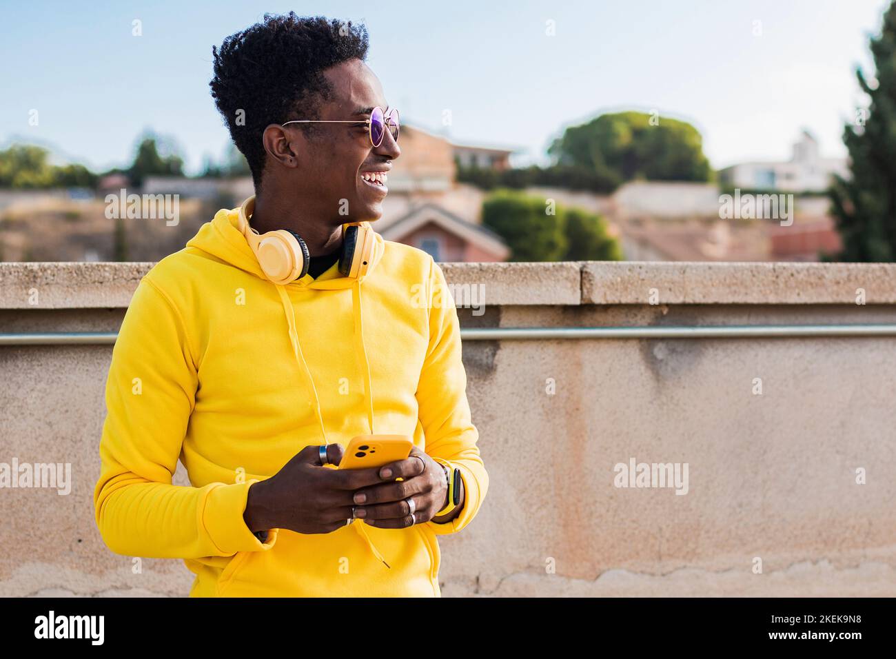 Portrait of a smiling young black man dressed in a yellow sweatshirt ...