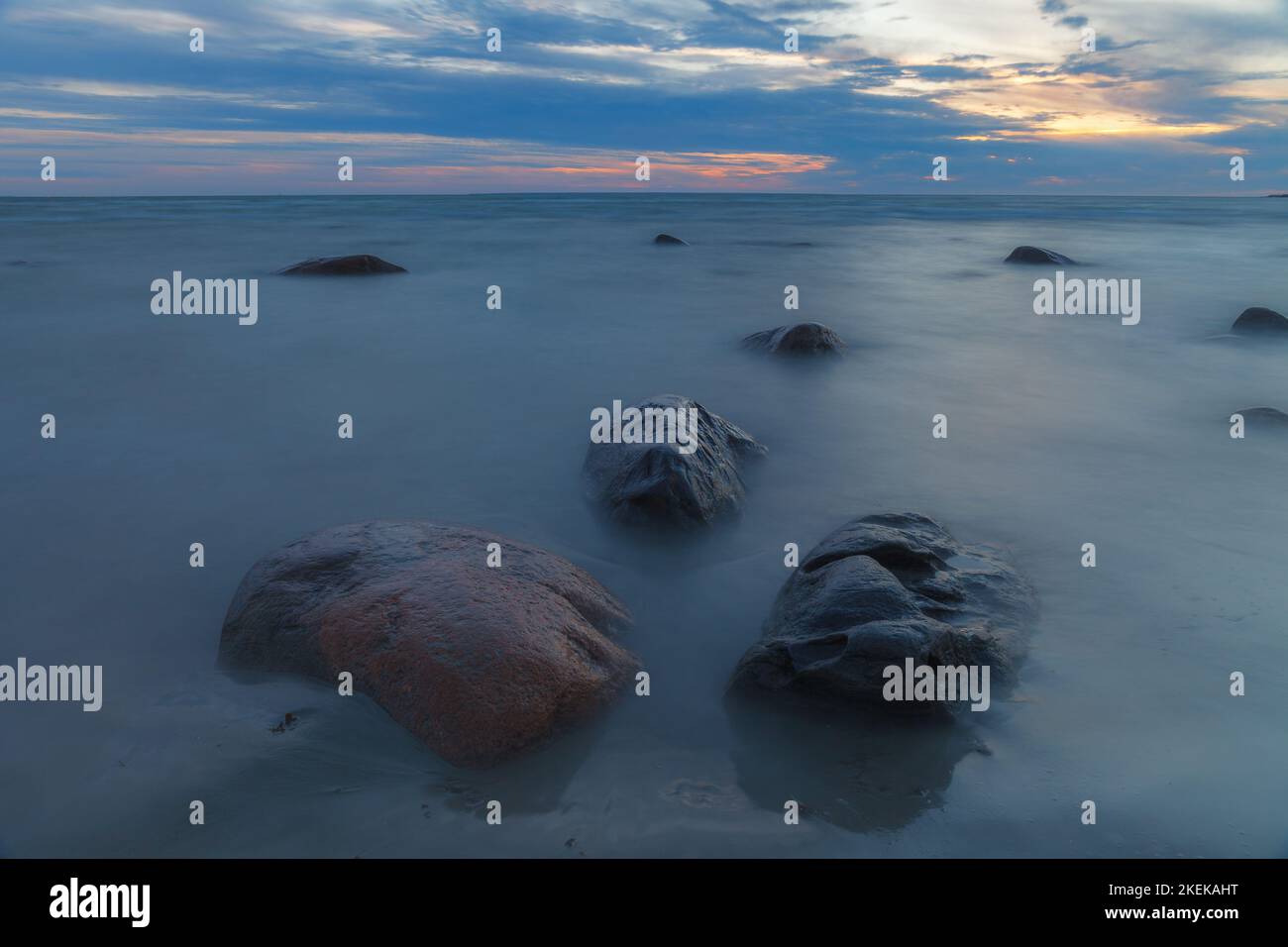Rocky shore of Baltic sea at sunset, sky is full of clouds, blue mood ...