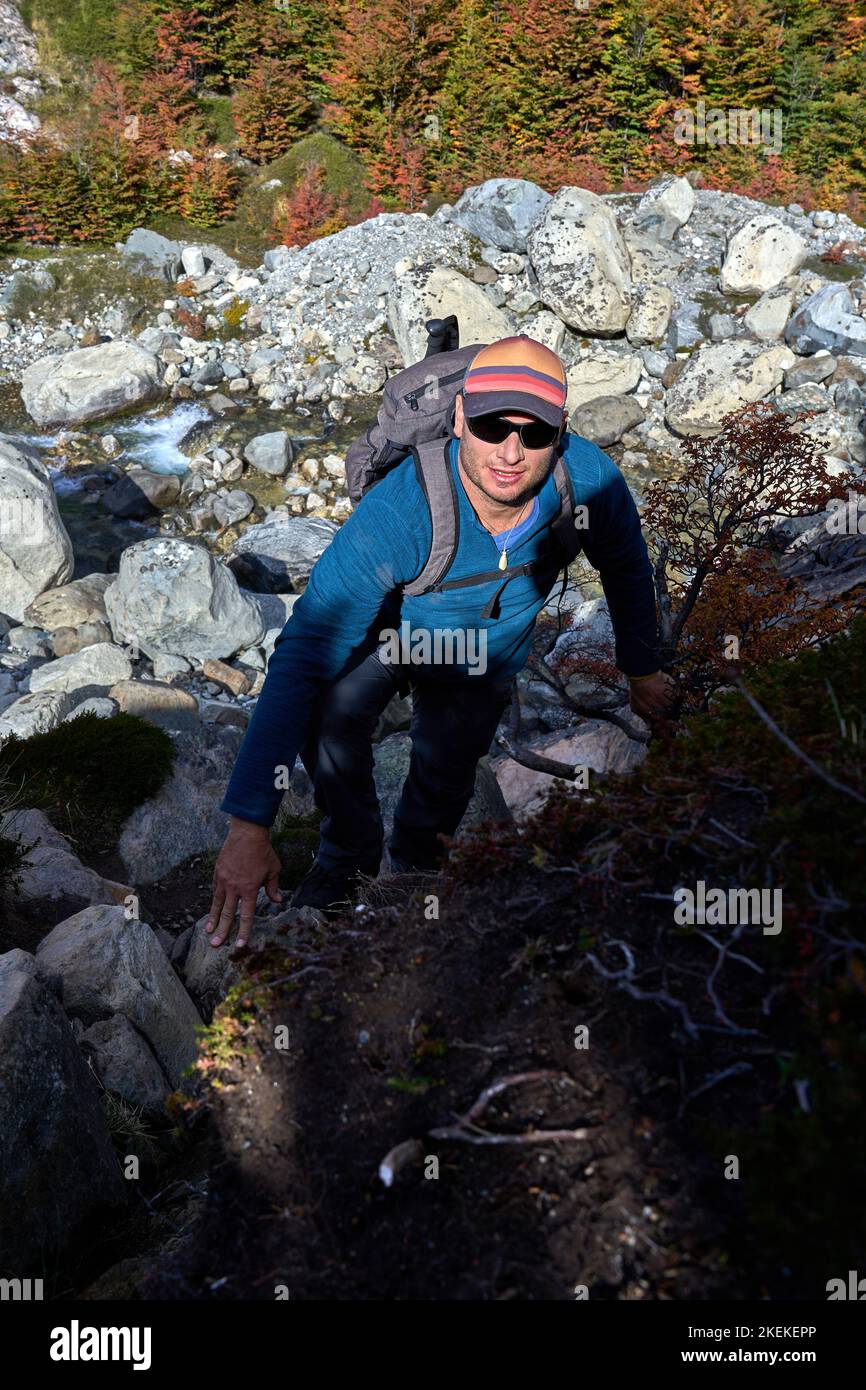40-year-old white man climbing a rock on a trekking trail in El Chalten ...