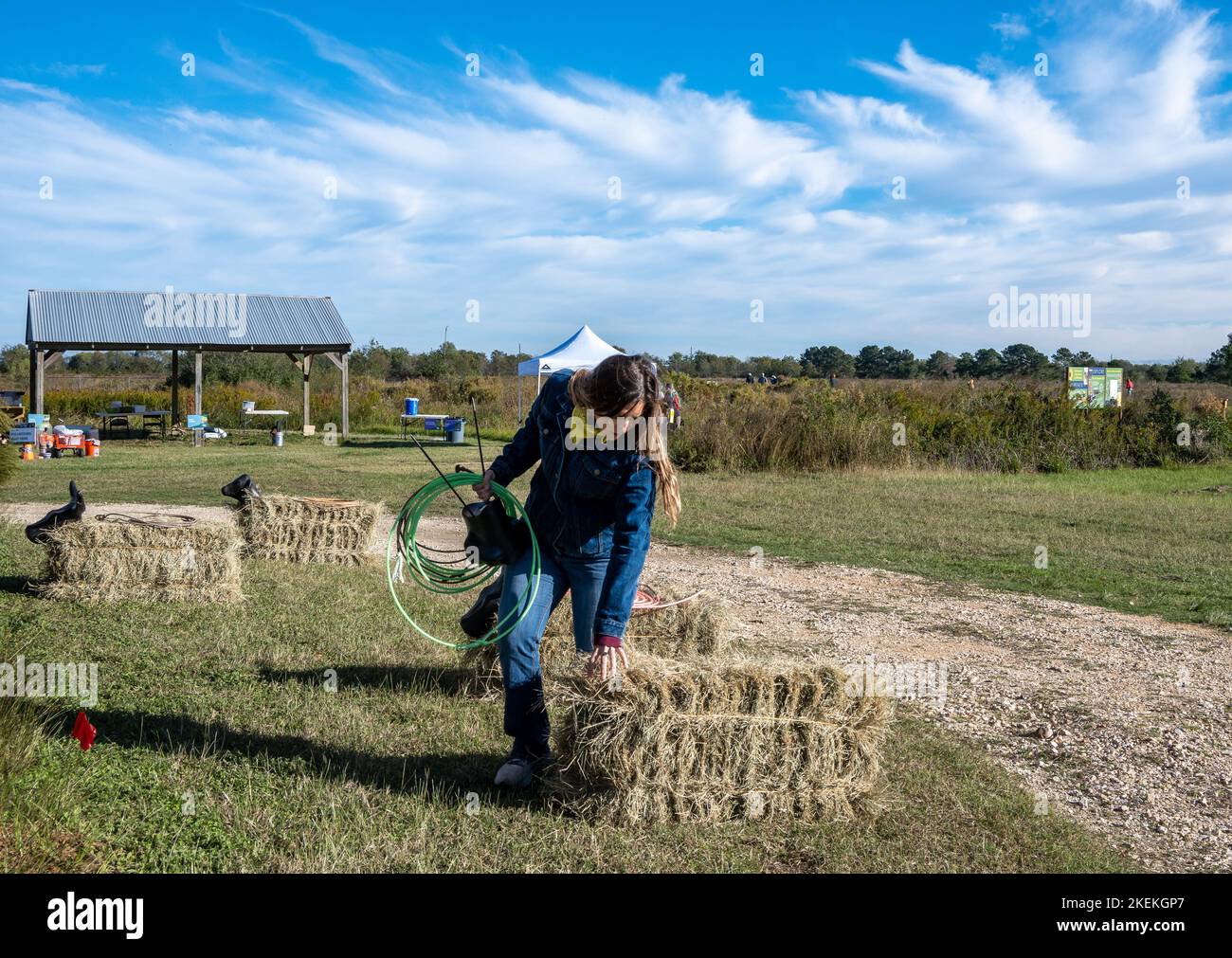 A young woman in blue jeans moves a hay bale at a local park. Houston ...