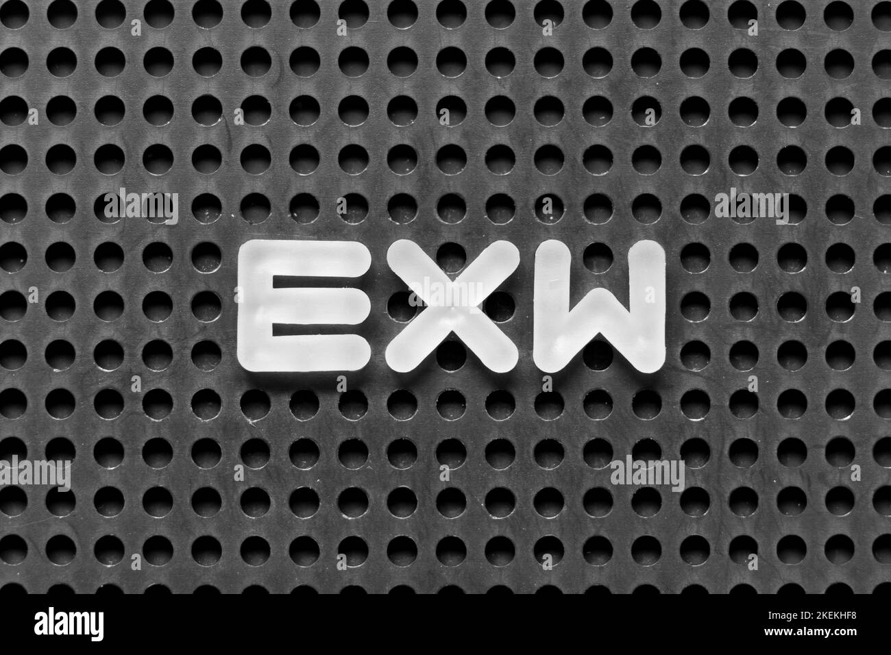 White alphabet letter in word EXW (abbreviation of Ex works) on black ...