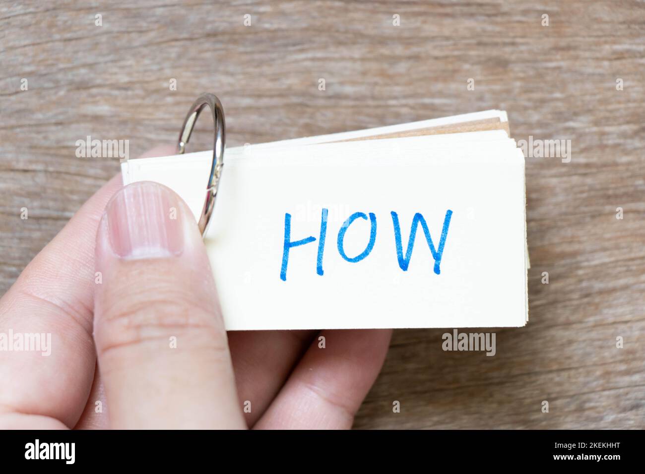 Hand hold flash card with handwriting in word how on wood background ...